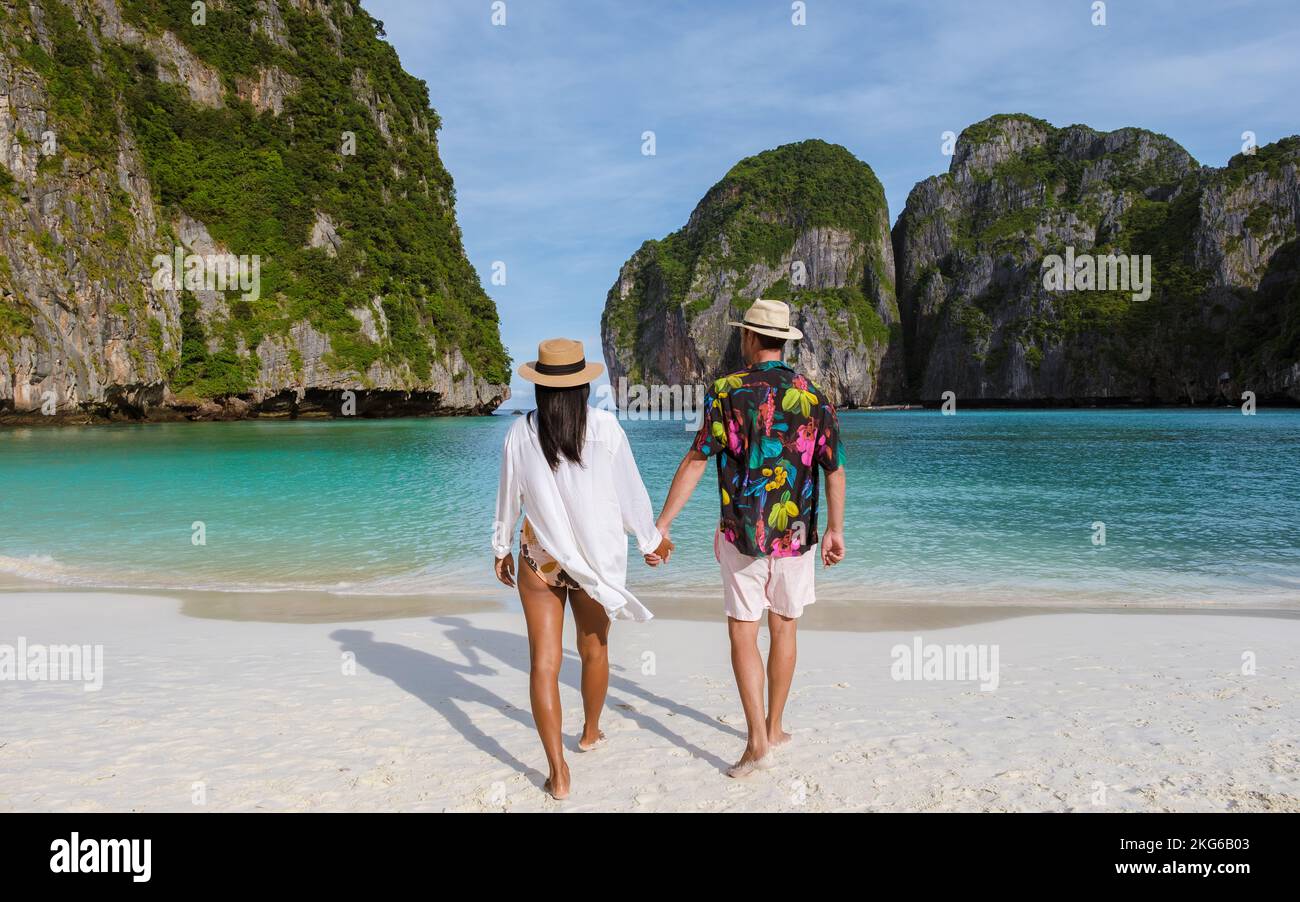 The backside of Thai women and caucasian men with a hat walk on the beach of Maya Bay, beach Koh ...