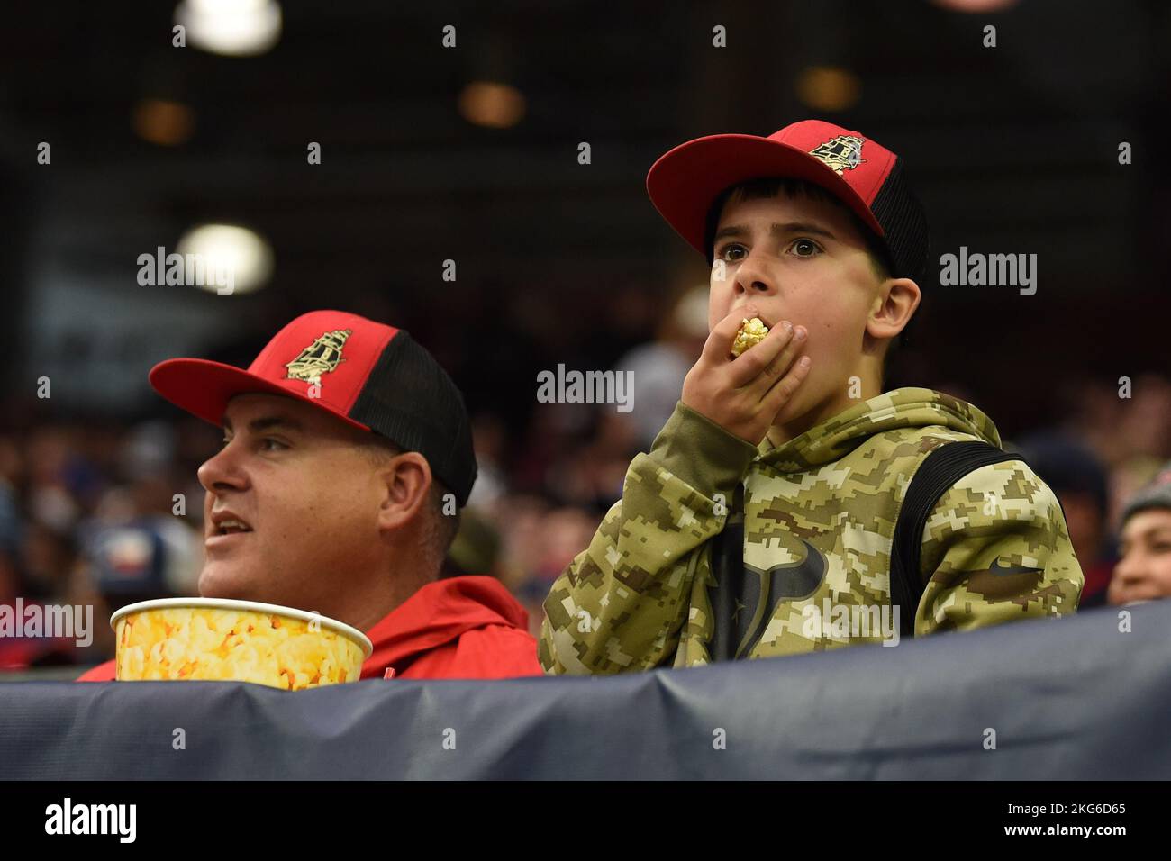 A young fan and his dad enjoy some popcorn while intently watching a ...
