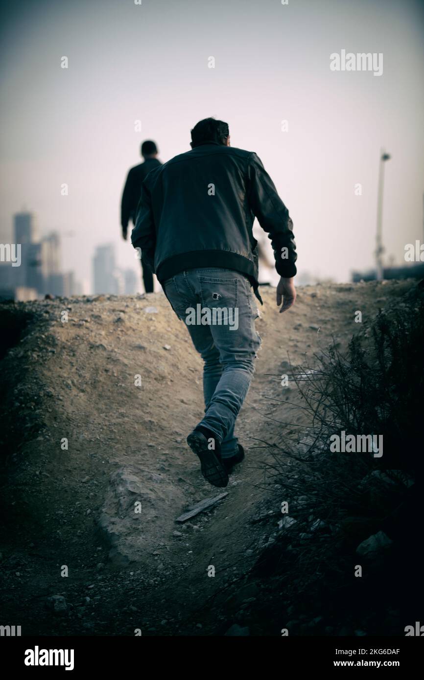 Criminal chasing a male victim outdoors Stock Photo - Alamy