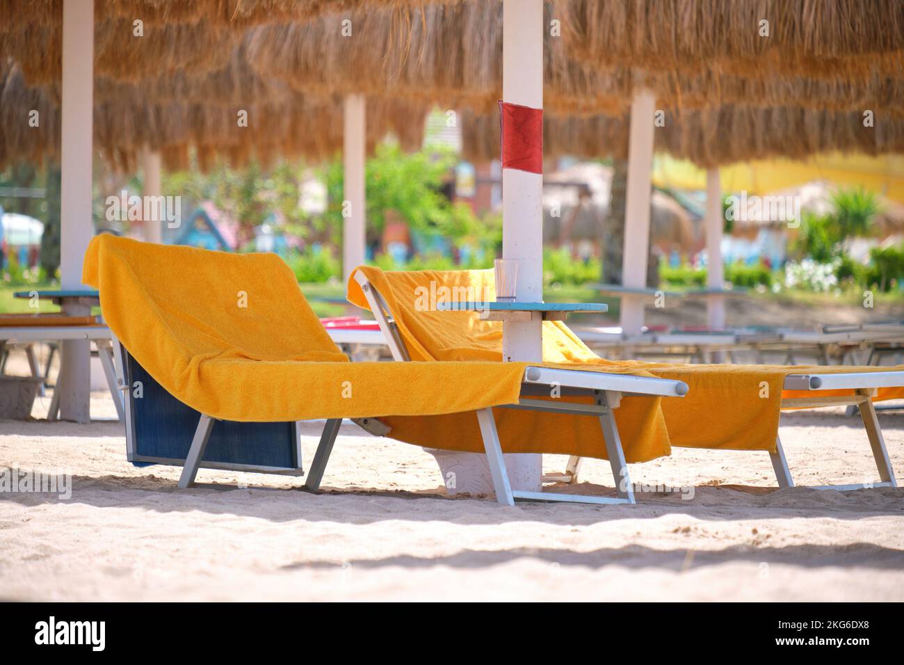 Straw shade umbrellas on sea tropical beach with resting sunbeds ...