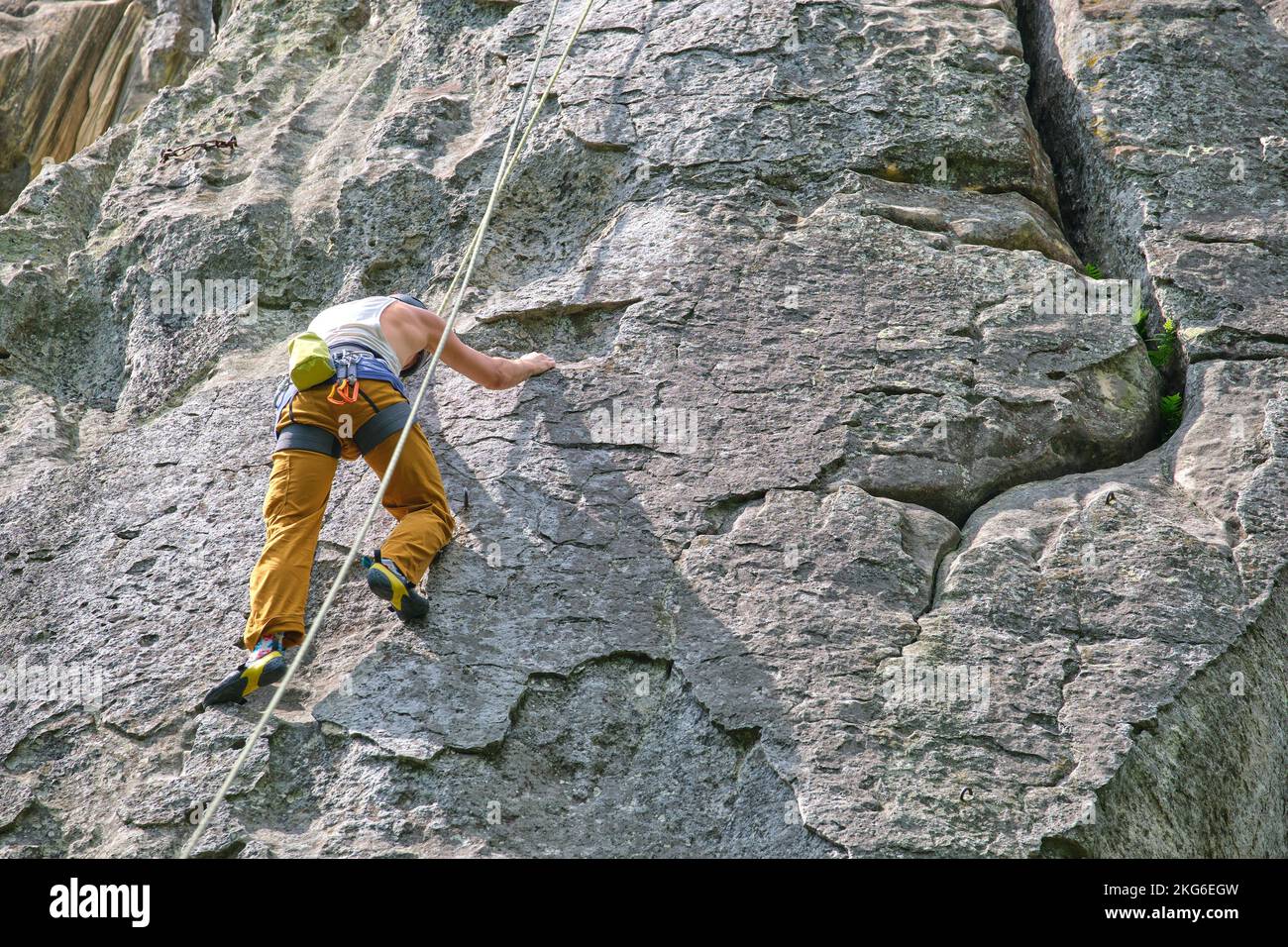 Strong male climber climbing steep wall of rocky mountain. Sportsman ...