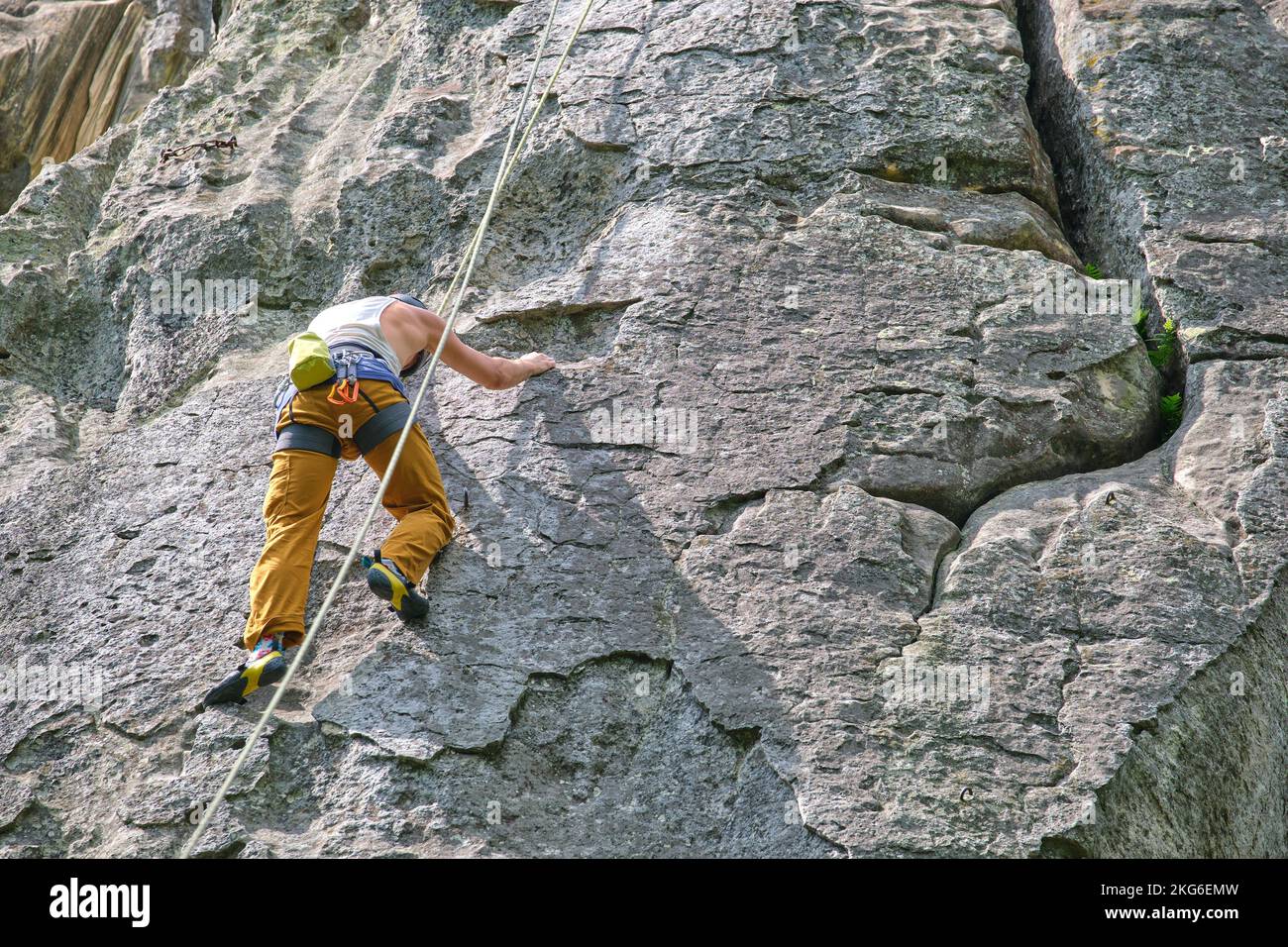 Strong male climber climbing steep wall of rocky mountain. Sportsman ...