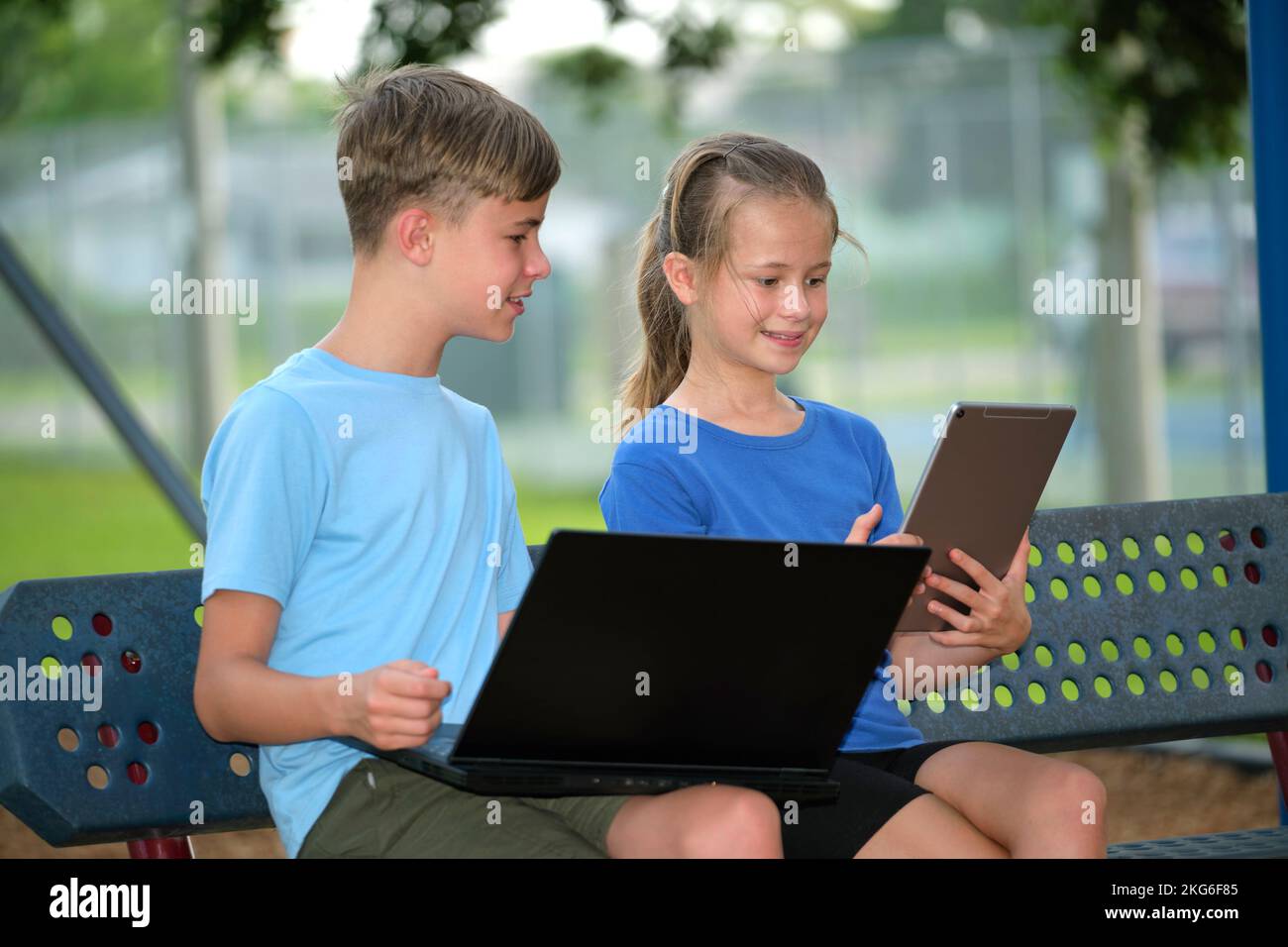 Two kids, teenager boy holding laptop computer and pretty young girl ...
