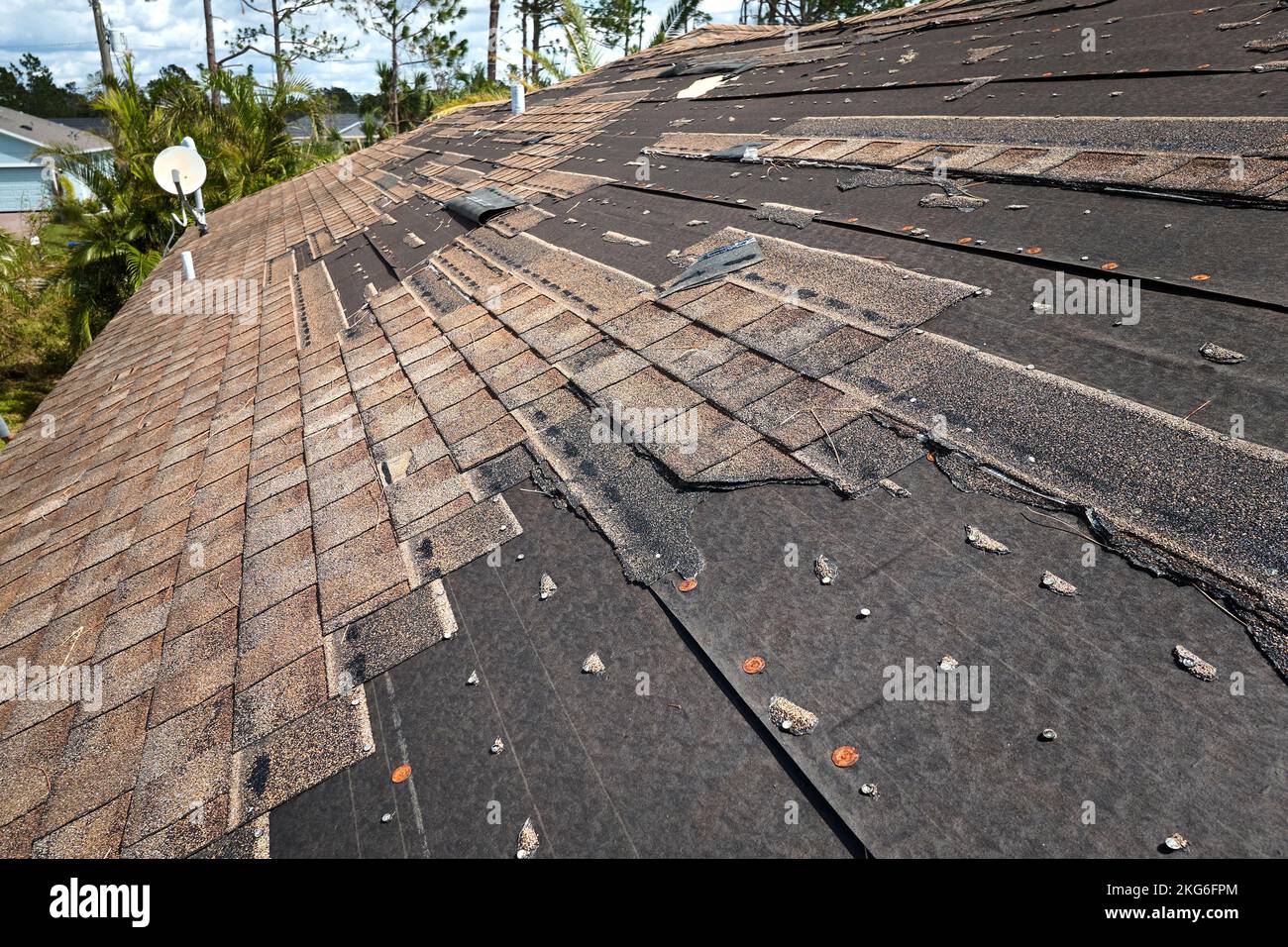 Wind damaged house roof with missing asphalt shingles after hurricane ...