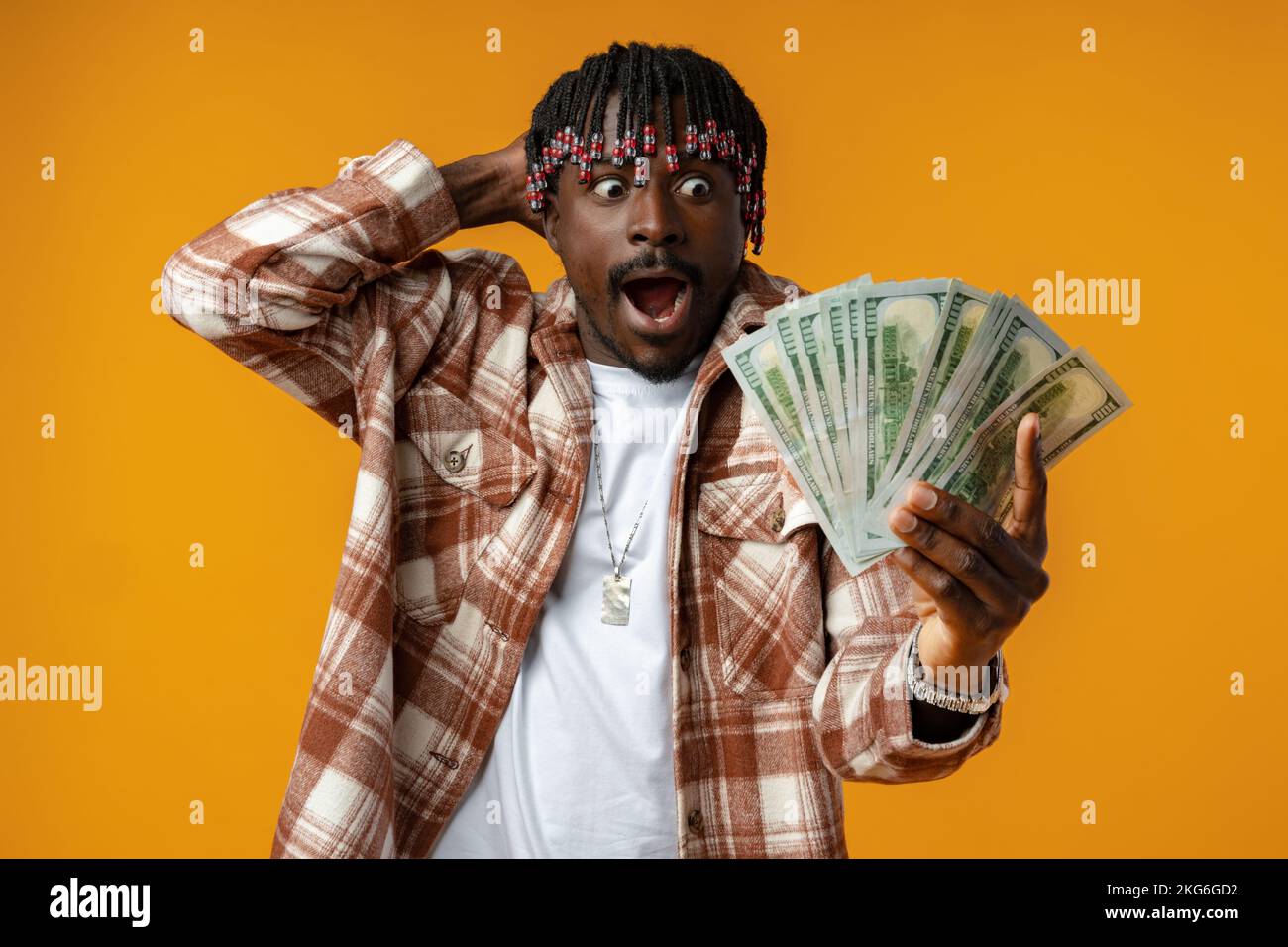 Young happy rich african man in casual shirt holding dollar bills ...