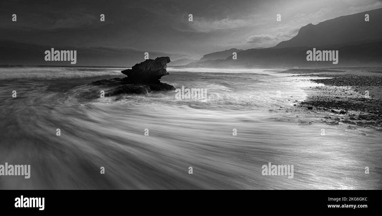 A greyscale shot of a long exposure of the ocean with big rocks Stock ...
