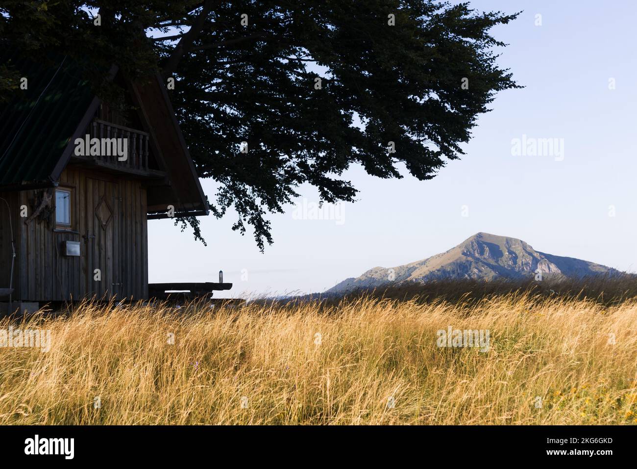 A wooden cabin in the field with a mountain background Stock Photo - Alamy