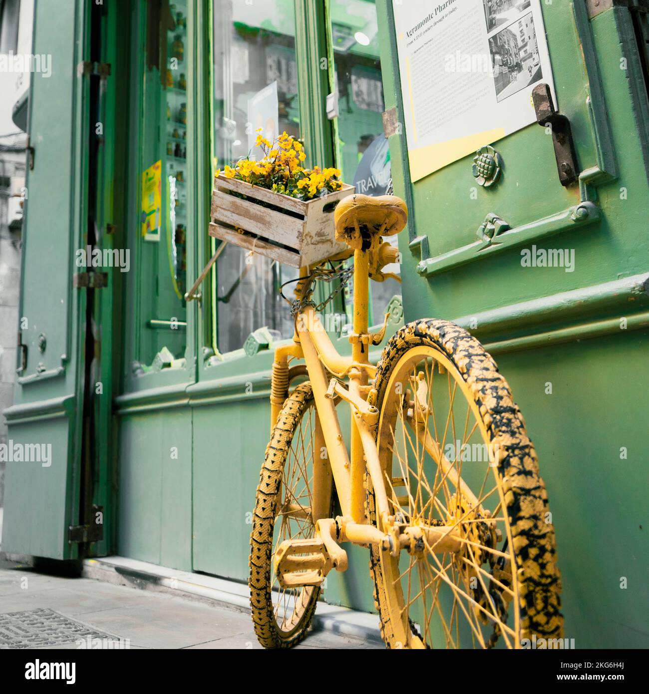 Yellow bicycle parked in front of a green house in an urban environment ...