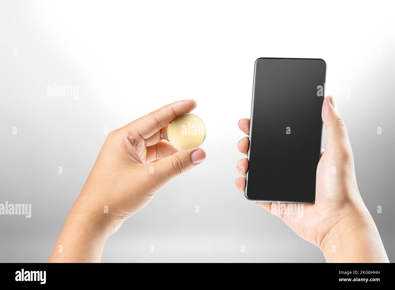 Hand holding mobile phone and coin on white background Stock Photo - Alamy