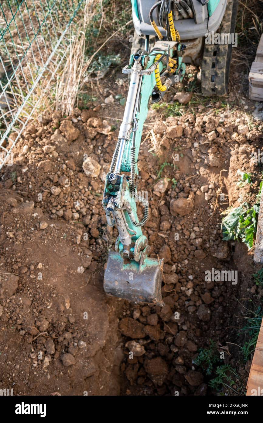 Mini excavator digs a trench to lay pipes. Close up of an excavator ...