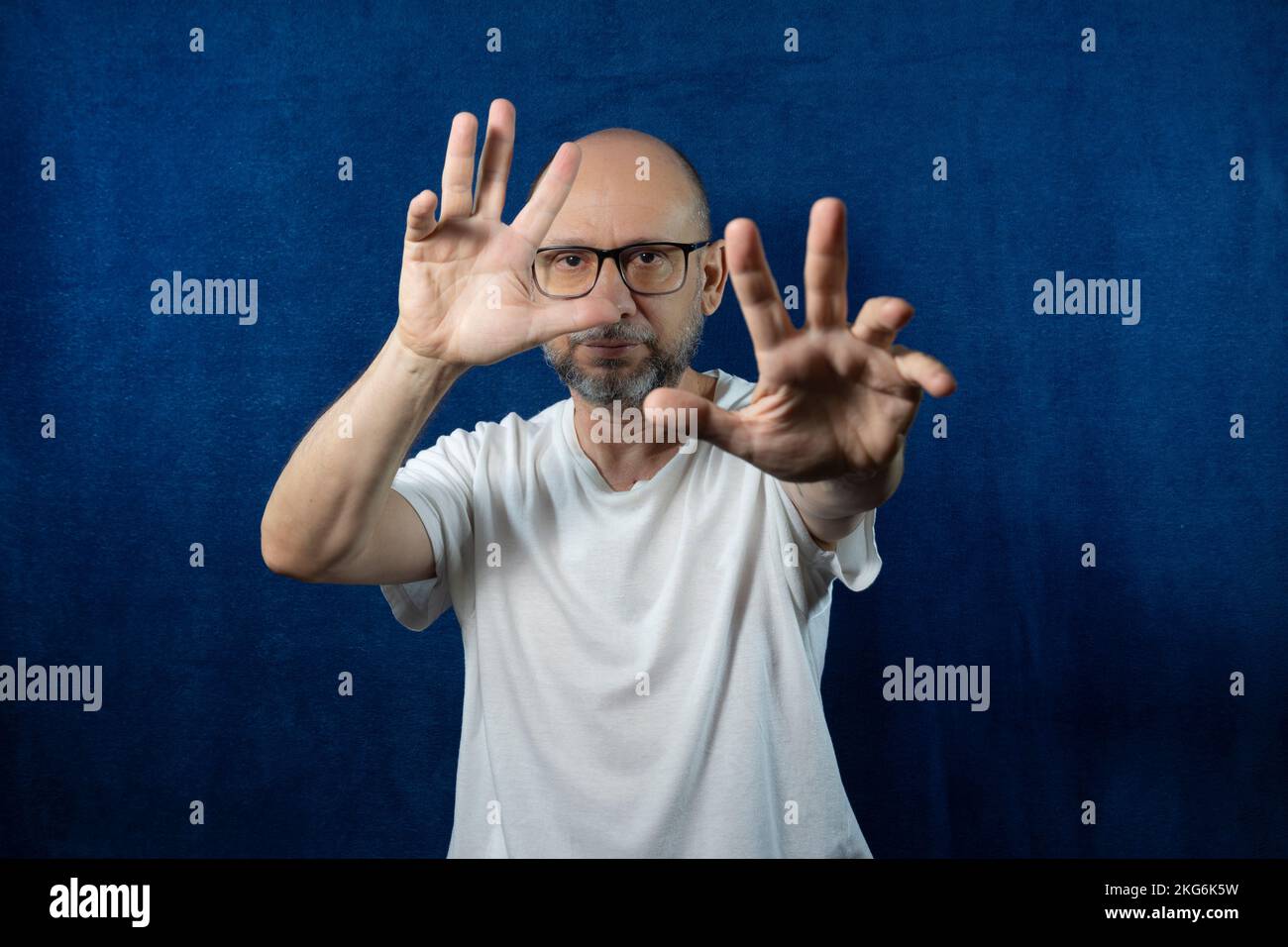 The portrait of a bearded bald man imitating something with his hands ...