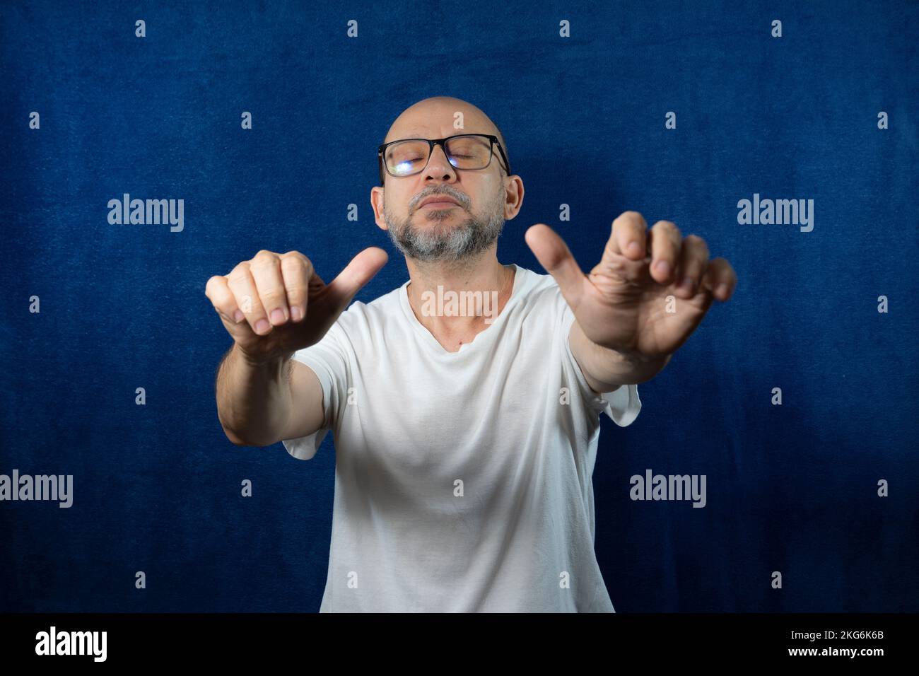 The portrait of a bearded bald man imitating something with his hands ...