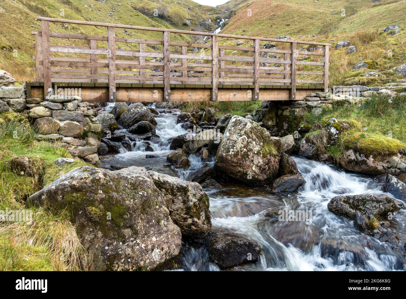 Wooden footbridge over river Red Tarn Beck, a tumbling mountain stream ...