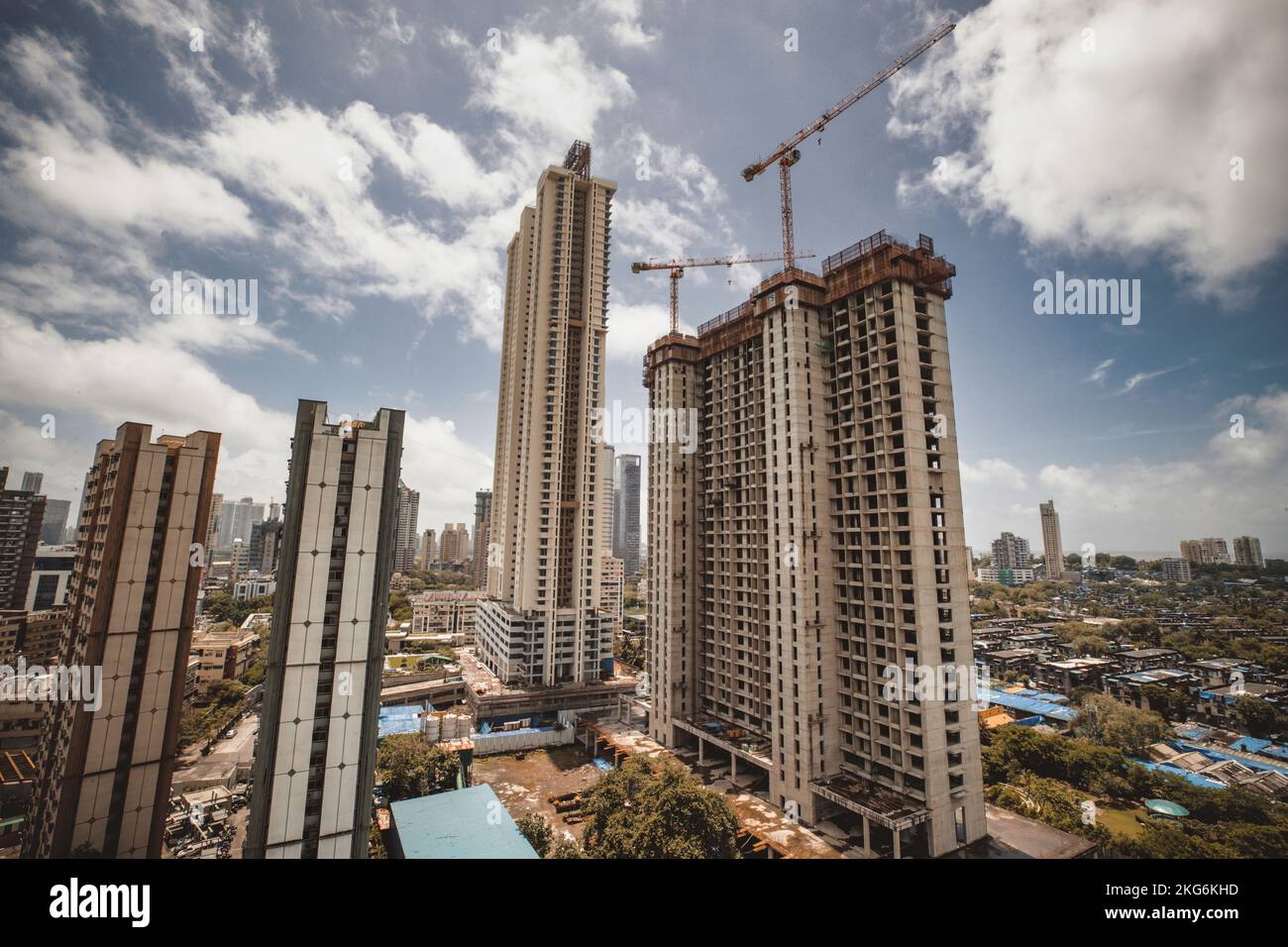 The large buildings with construction cranes under a blue sky with ...