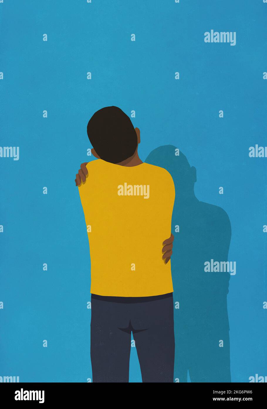 Man hugging himself at blue wall Stock Photo - Alamy