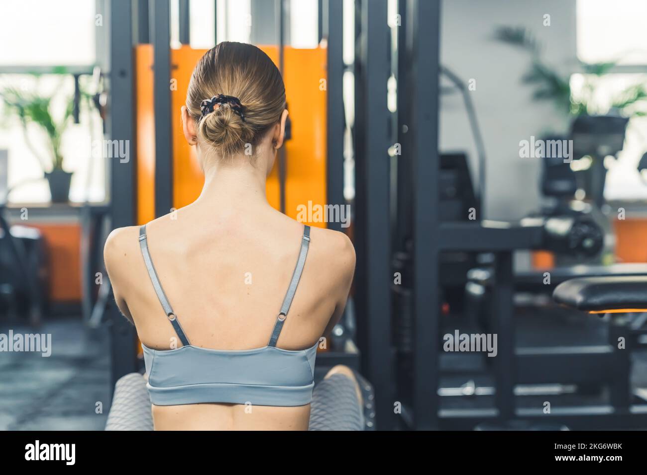 Back of a young, slim, caucasian woman with blond hair in a bun working ...