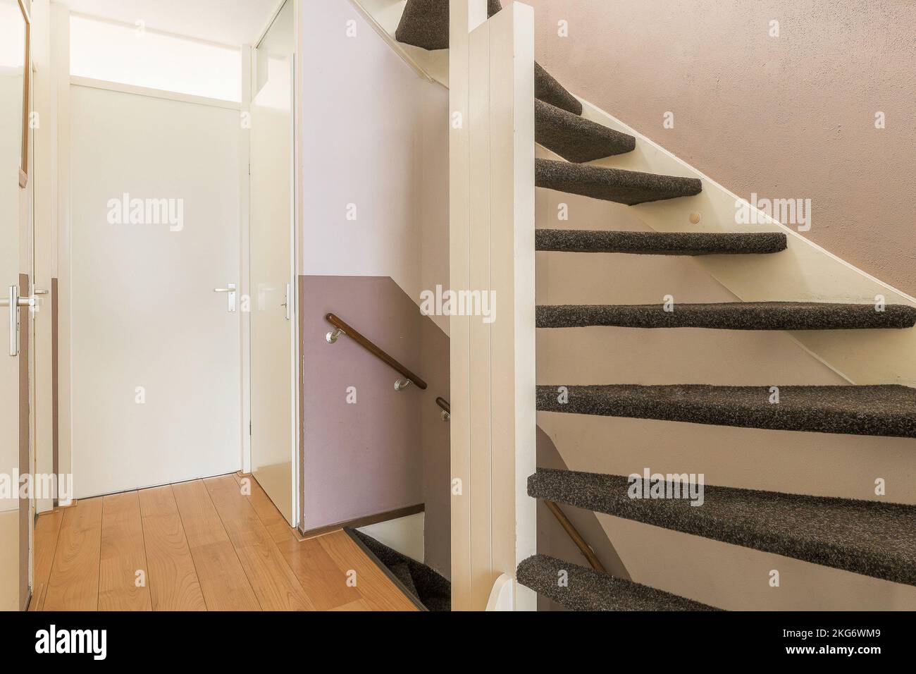 White hallway with wooden stairway leading to second floor Stock Photo ...
