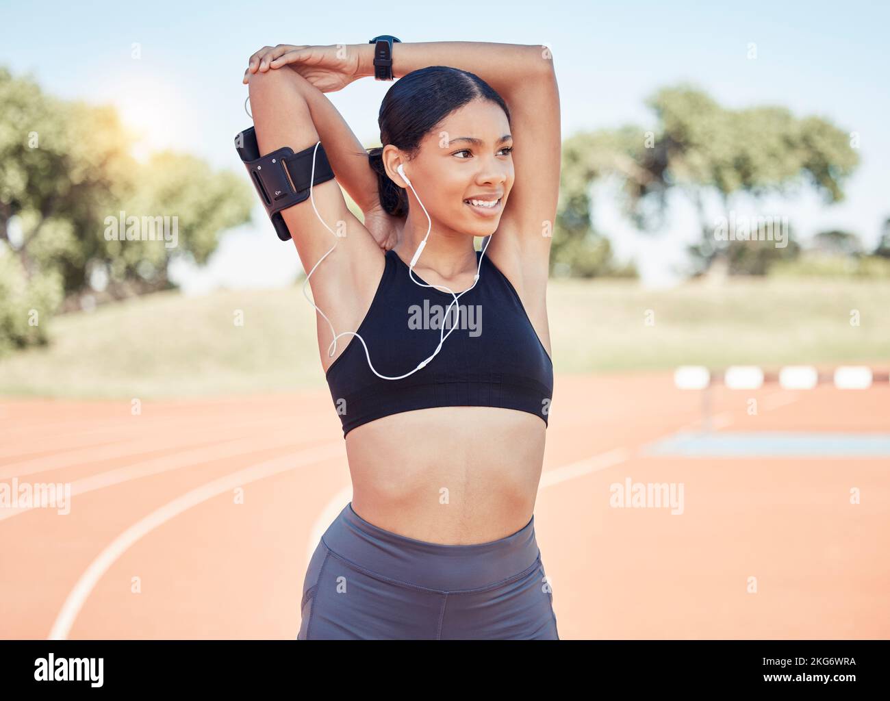 Woman runner, earphones and stretching arms on track for sports ...