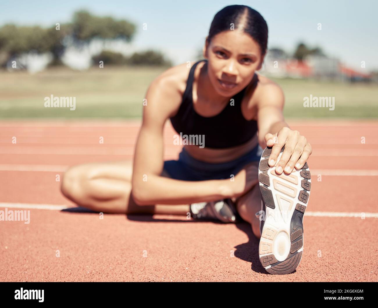 Stretching, feet and sports woman at stadium or race track with fitness ...