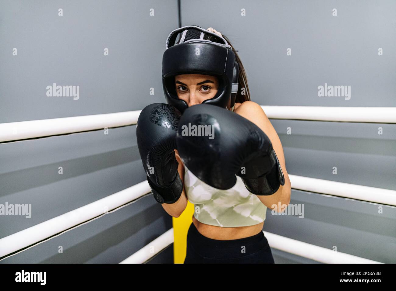 Woman with protective gloves and headgear in attack position on a ring ...