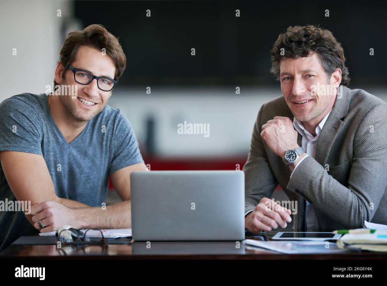What can we do for you. two businessmen looking over some work Stock ...