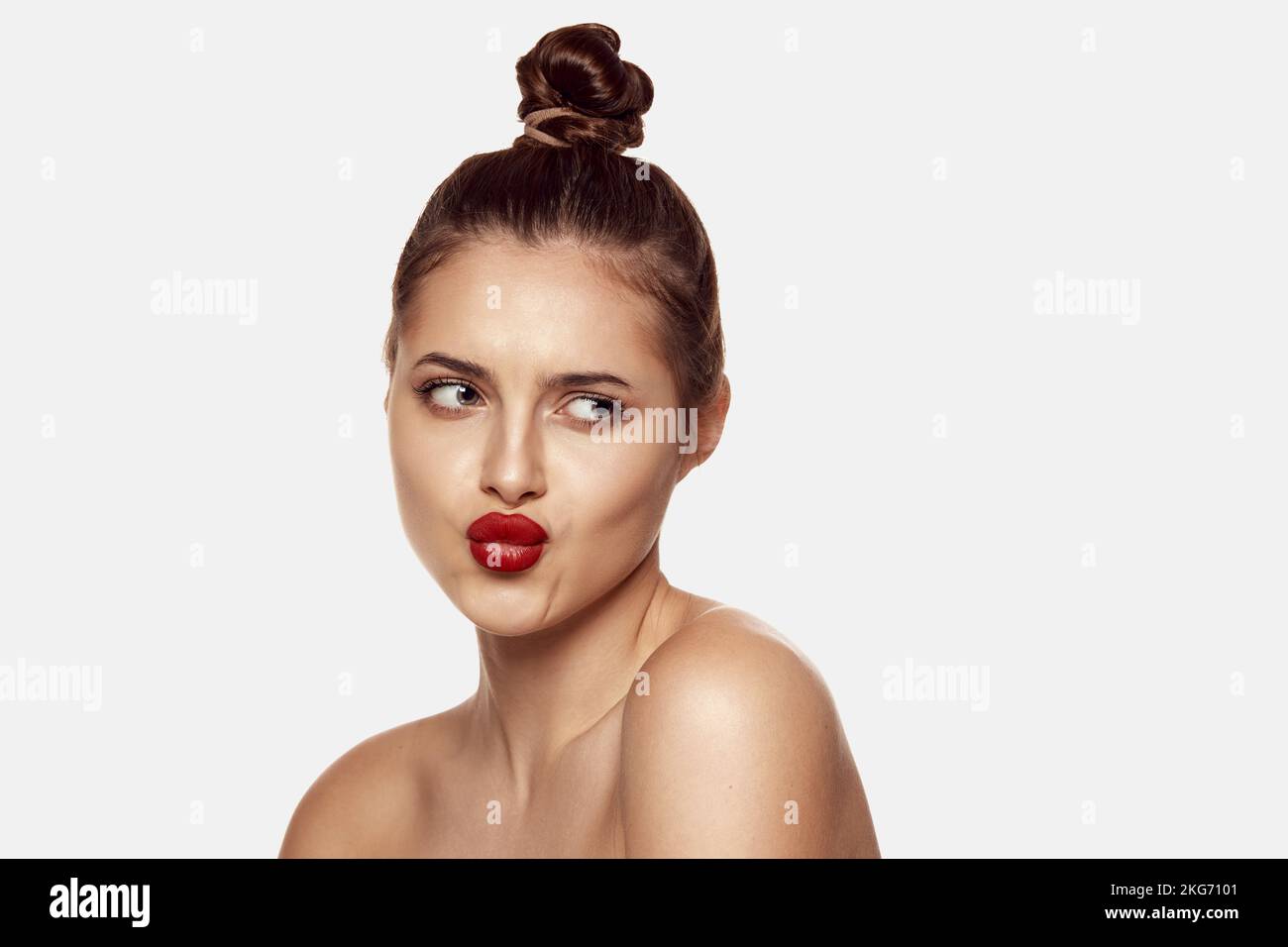 Portrait Of Young Beautiful Girl Posing With Hair Bun And Red Lips Isolated Over White