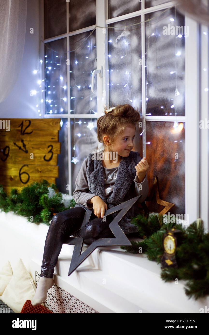 Cute little girl sitting by the window and waiting for Holiday Stock ...