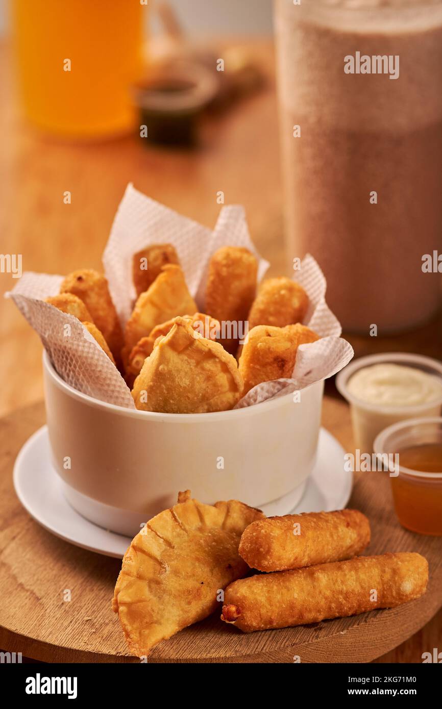 A vertical close-up of fried rolls and samosas on a wooden board on the ...