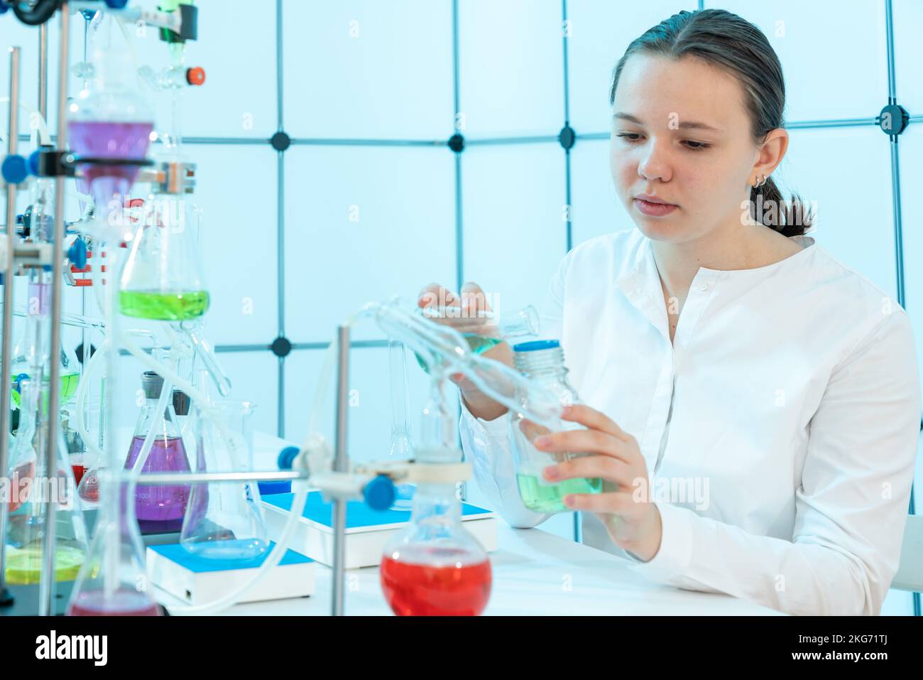 young woman in a chemical laboratory analyzes the water from the river for the presence of toxic ...