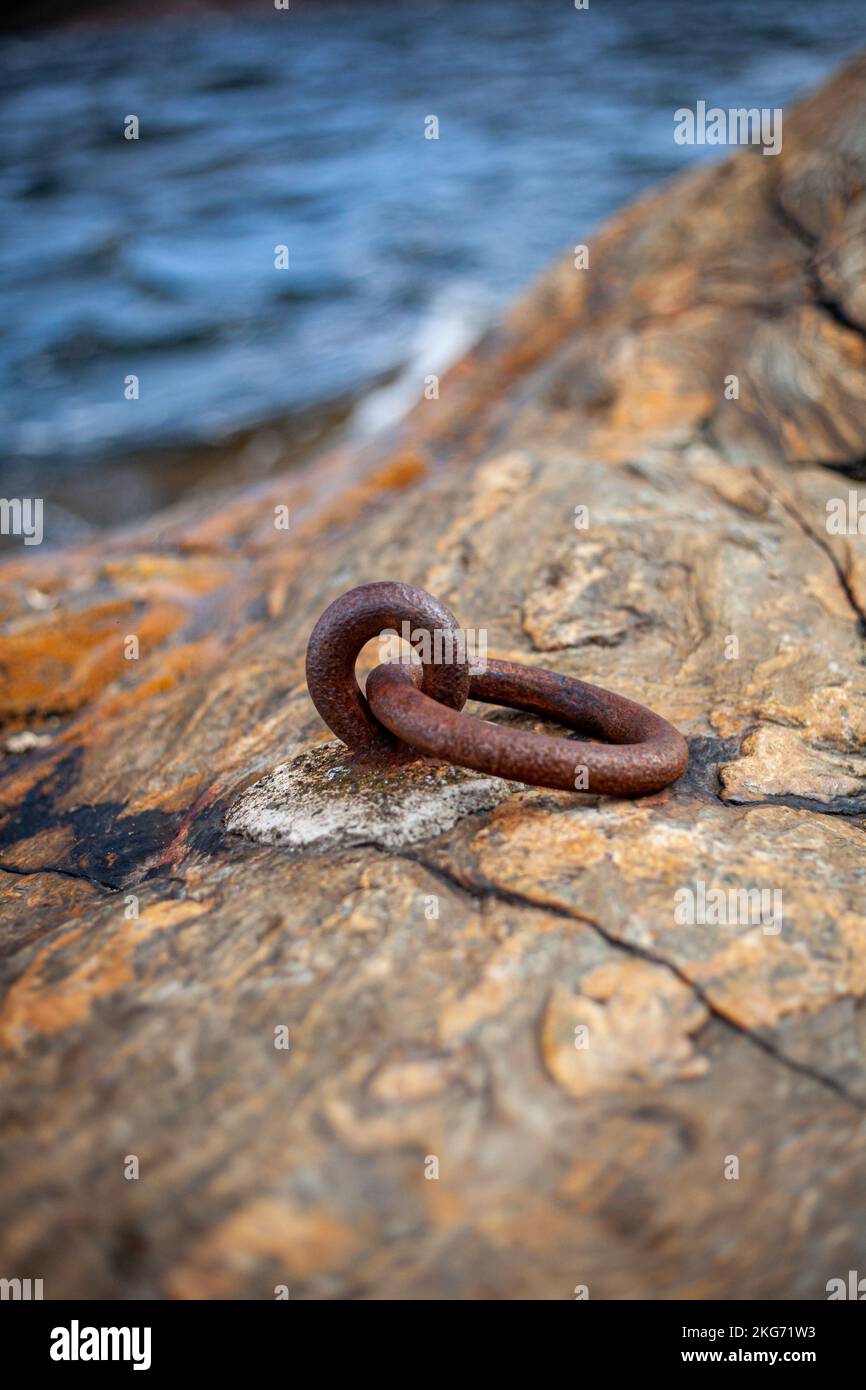 A vertical shot of a rusty ring set in stone to tie boats on the ...