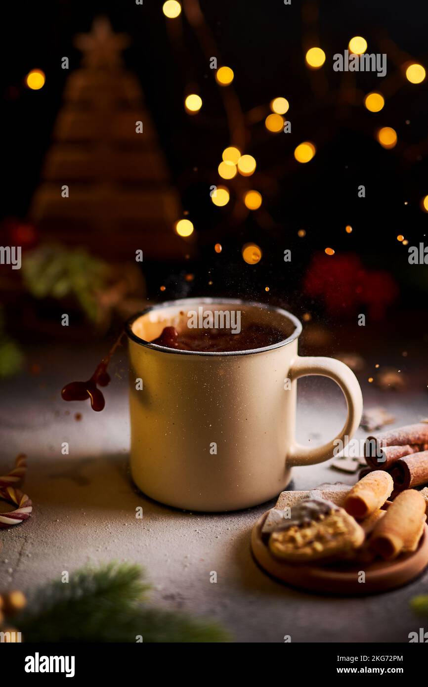 Mug of hot chocolate with splash surrounded by Christmas decorations ...