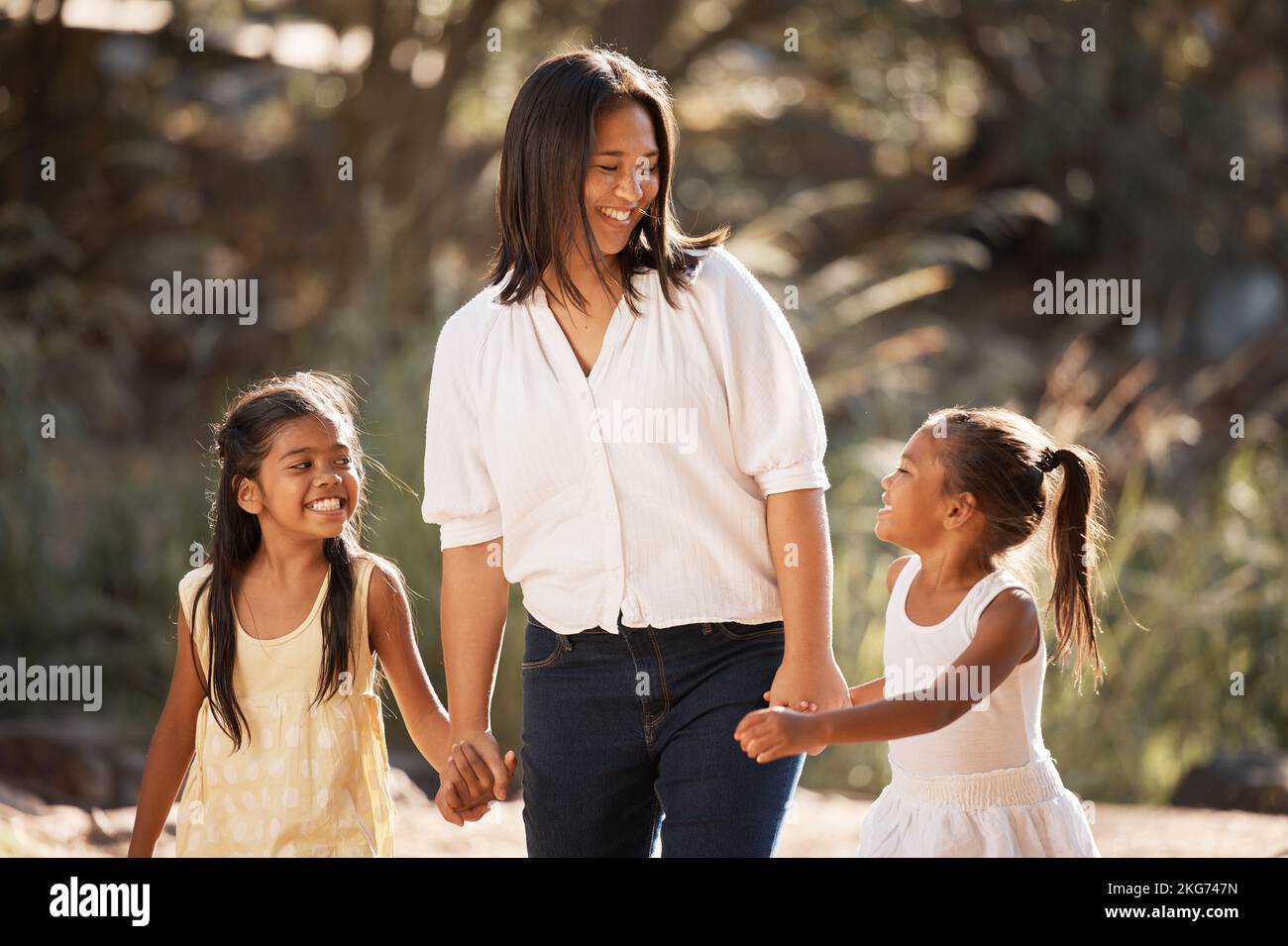 Family, children and holding hands with a mother and daughter siblings walking outdoor together ...