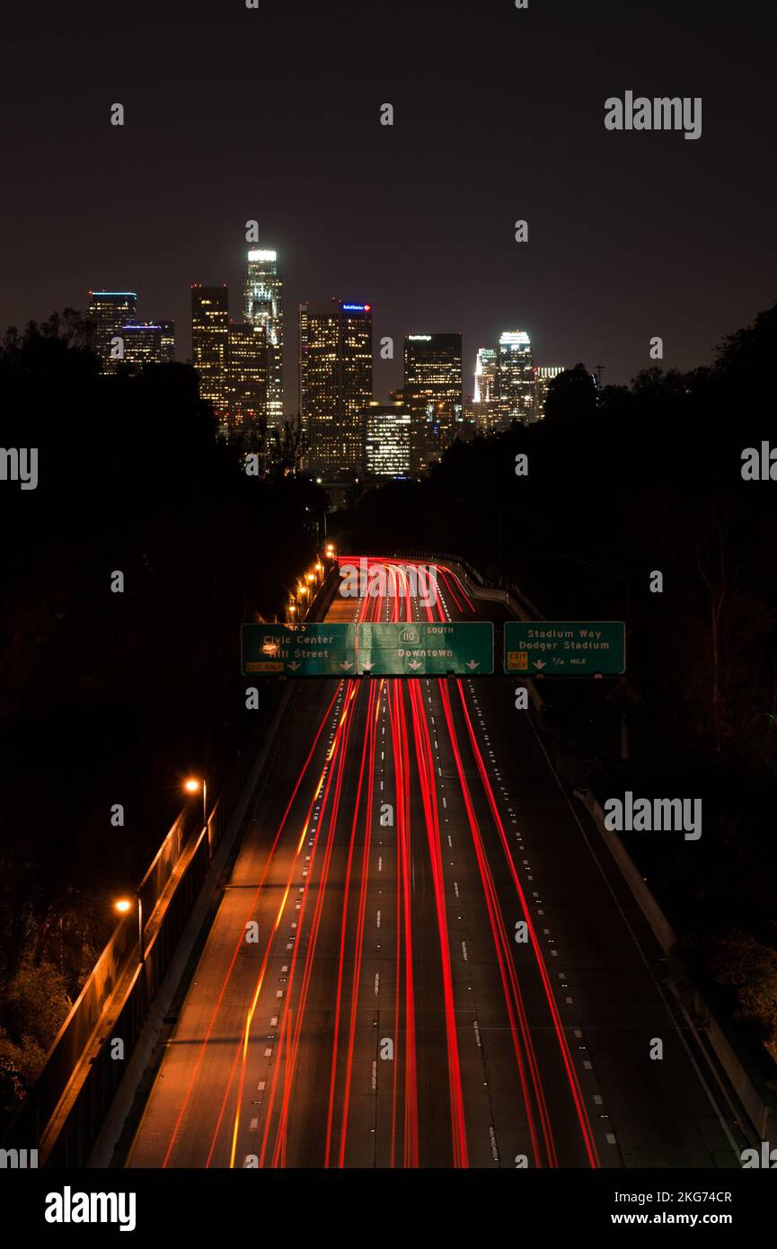 A vertical top view of highway light trails against the city lights of ...
