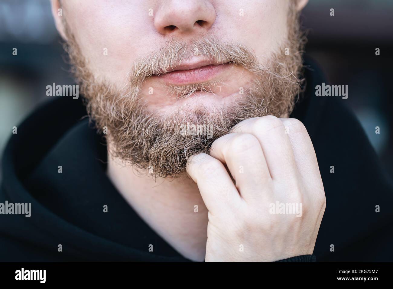 Close-up, a young man touches his beard with his hand Stock Photo - Alamy