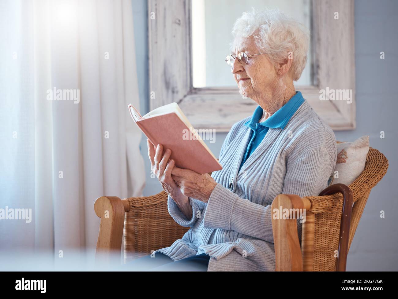 Book, reading and senior woman in home retirement with glasses and calm ...