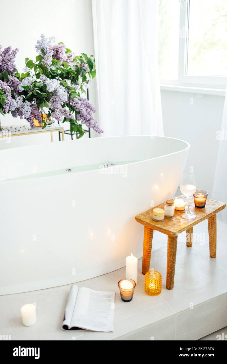 Modern bath room and spa center on the white tub wooden table. Candles ...