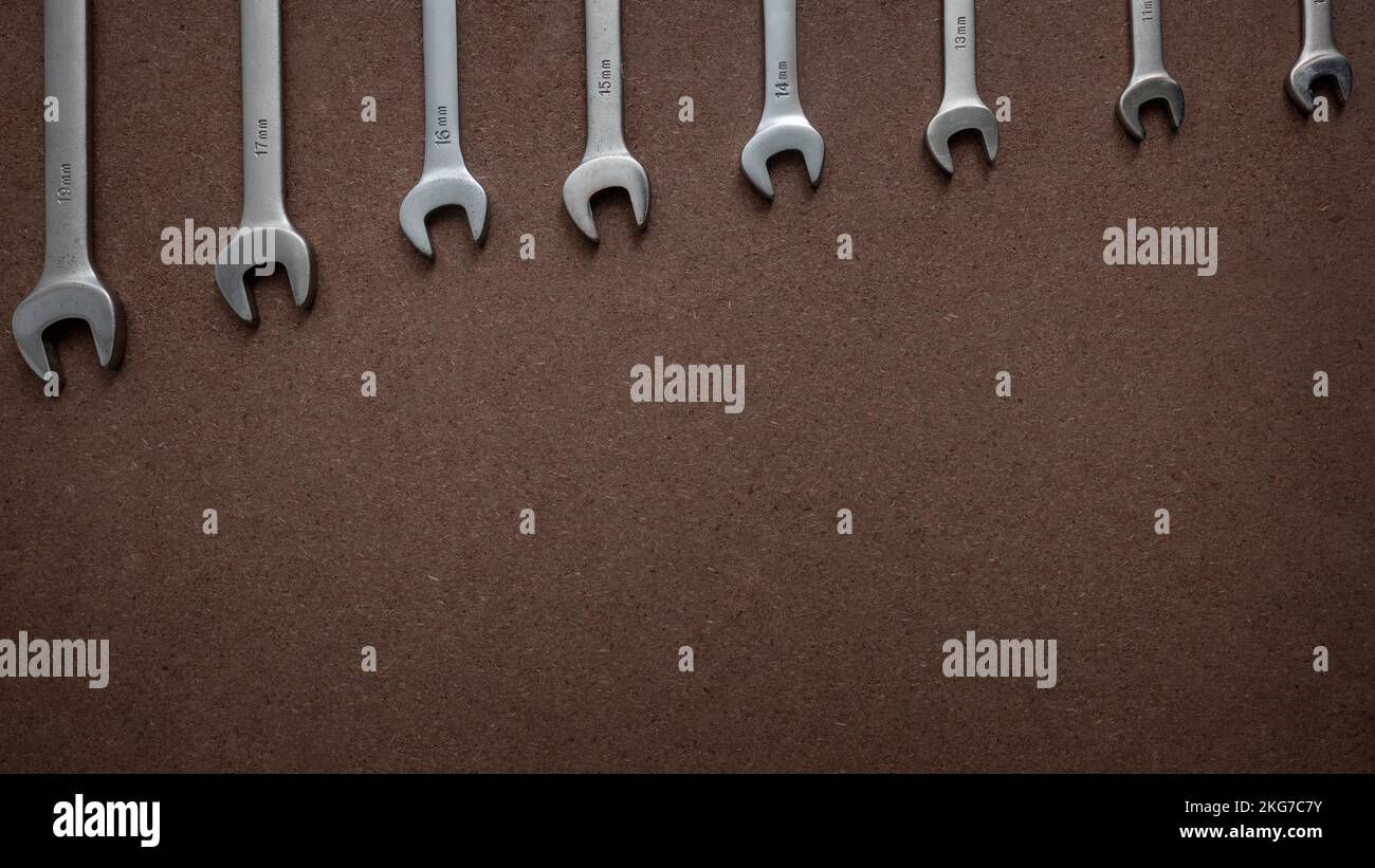 Spanners with different sizes on a wooden board. Top down view flat lay ...