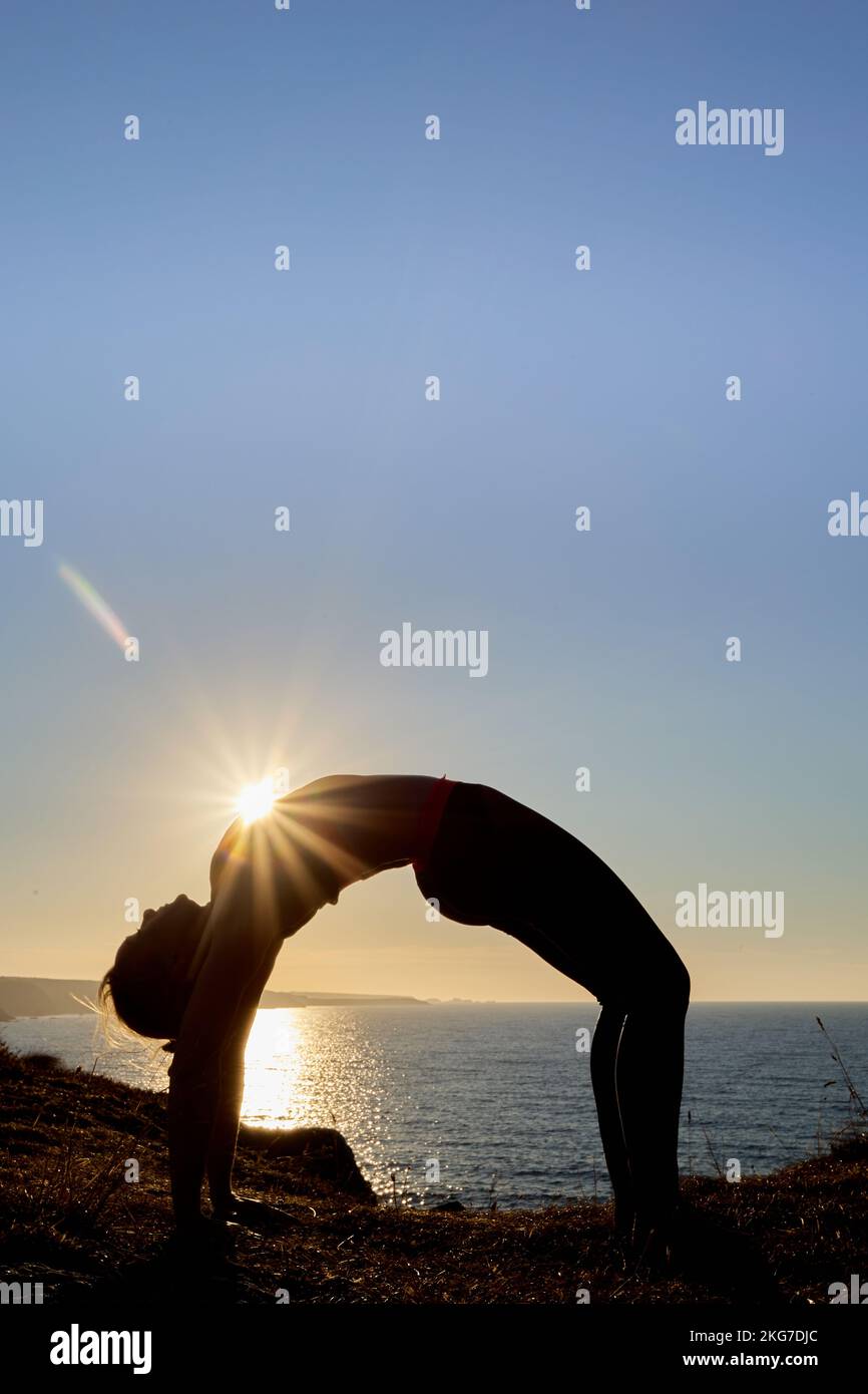 silhouette of woman with nice body performing inverted yoga pose at ...