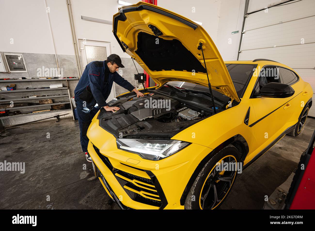 Mechanic open hood of yellow sport car suv Stock Photo - Alamy
