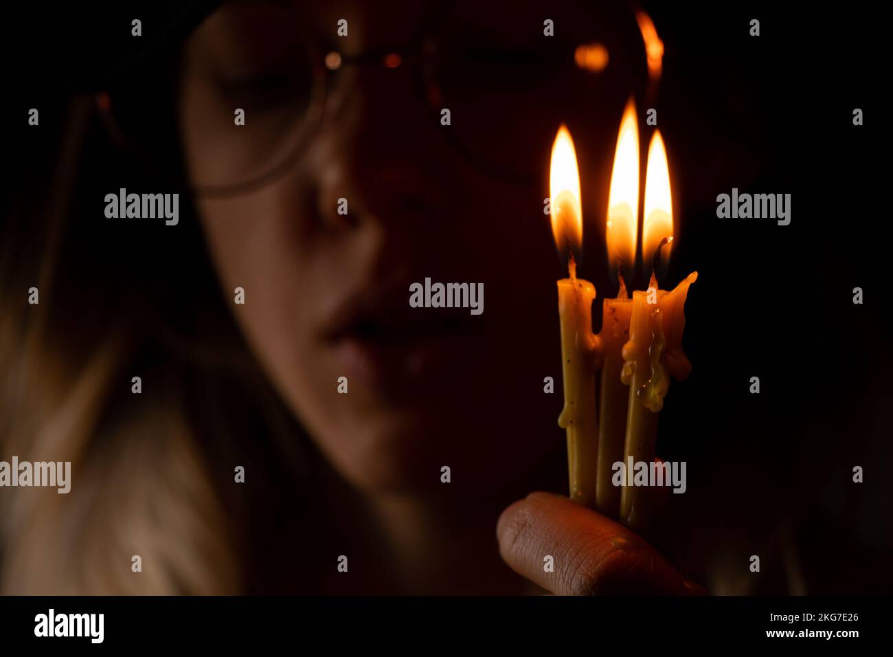 a girl in a black hat in the dark holds a candle, a girl with candles ...