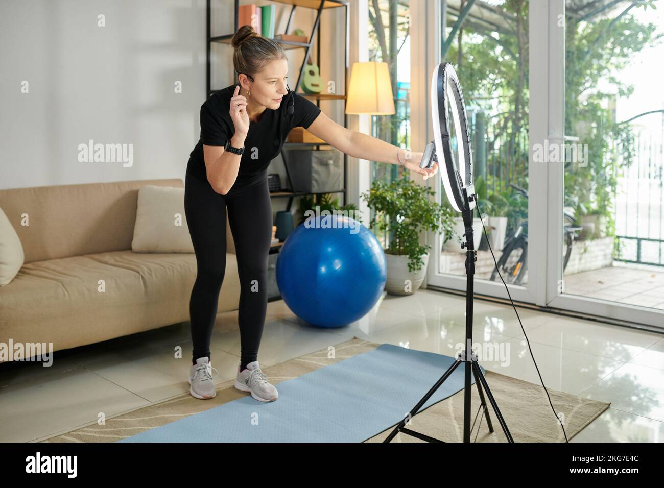 Online fitness instructor setting smartphone and ring lamp to film ...