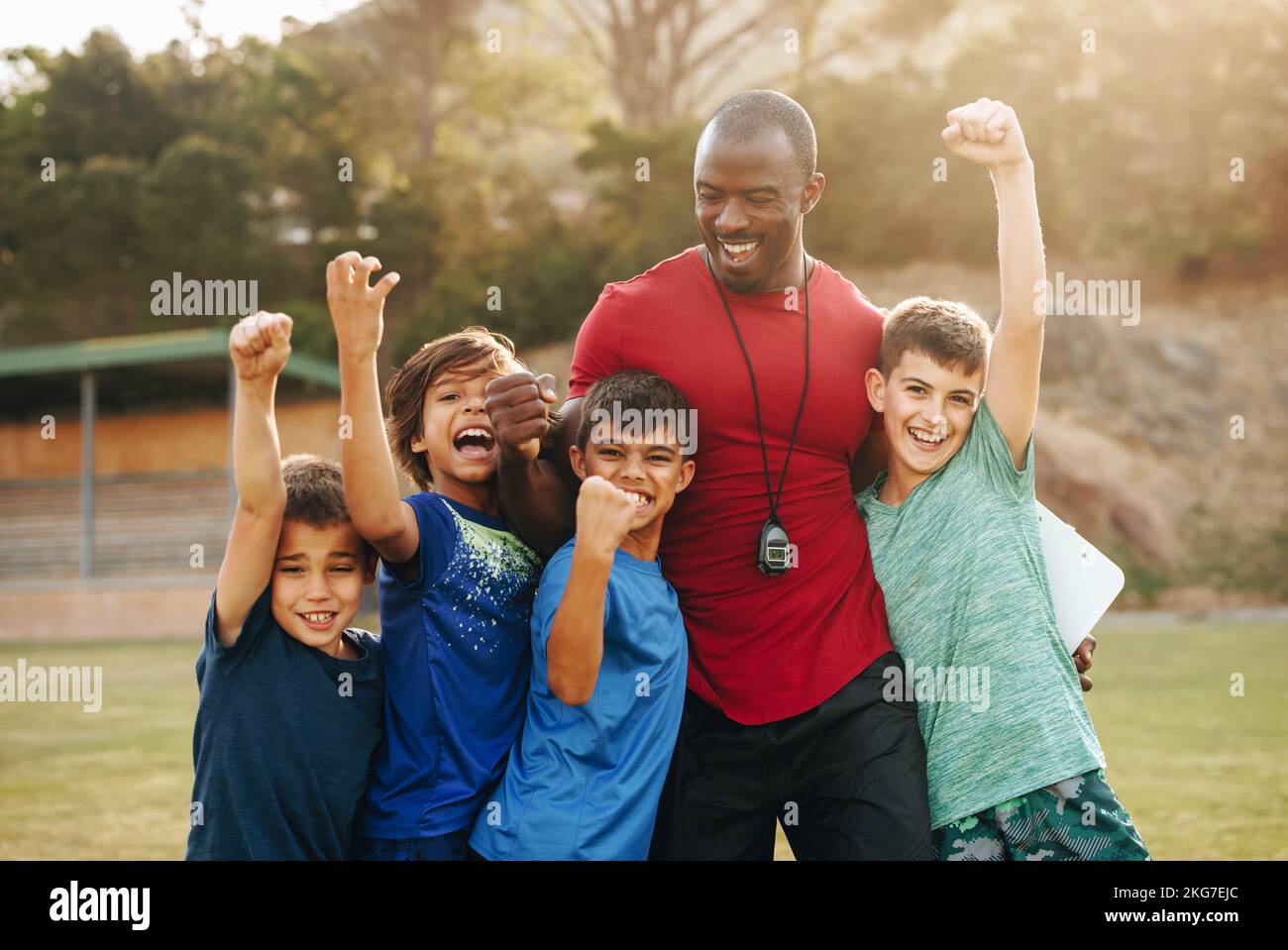school kids celebrating with their coach on a sports field. Elementary ...
