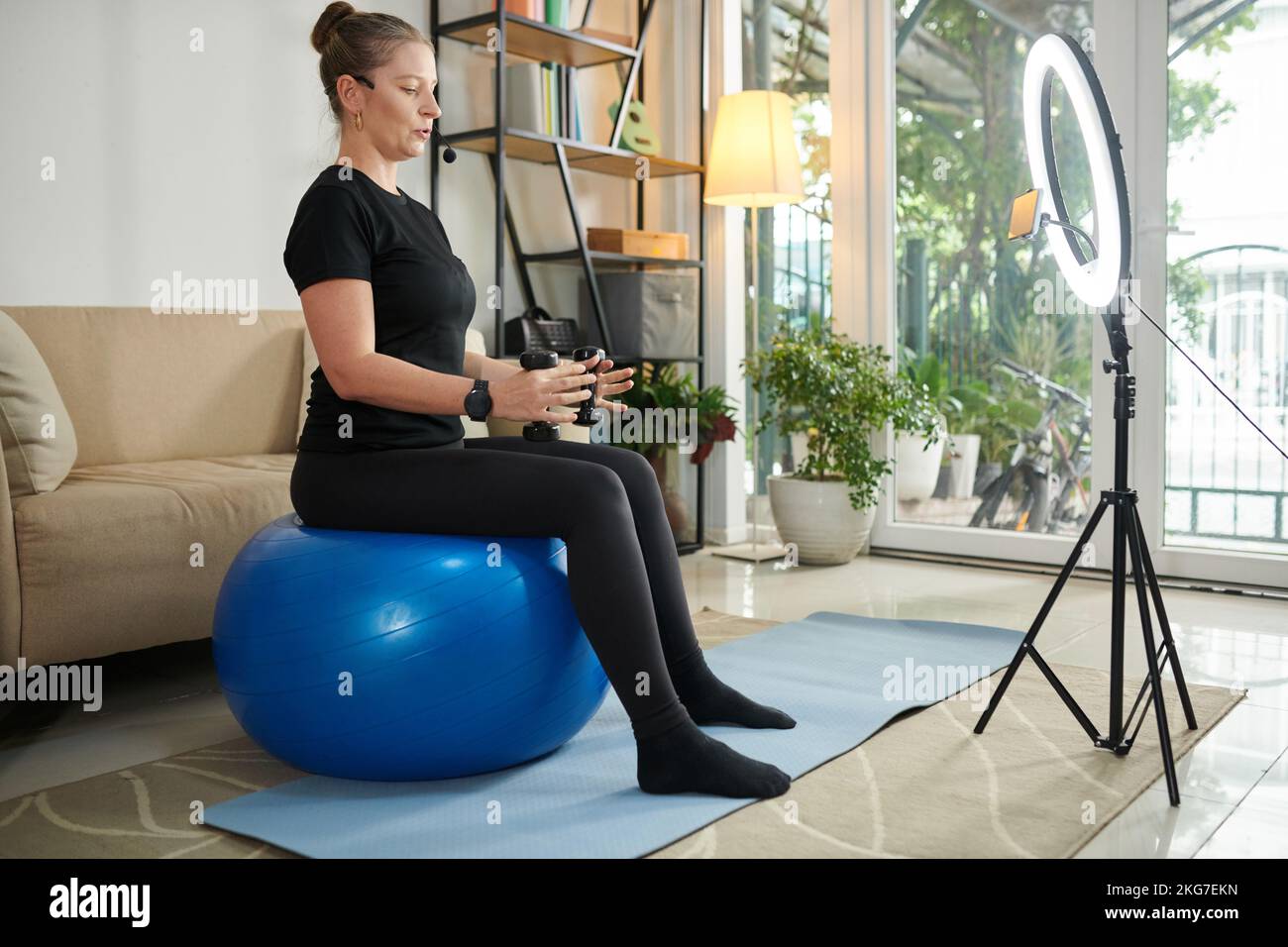 Online fitness trainer working out with dumbbells in front of camera ...