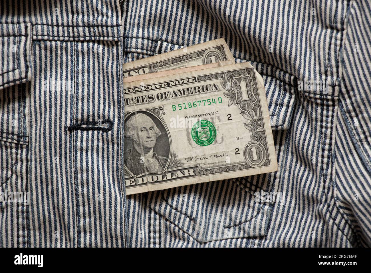 one dollar is in the pocket of a striped denim jacket, a dollar is in ...