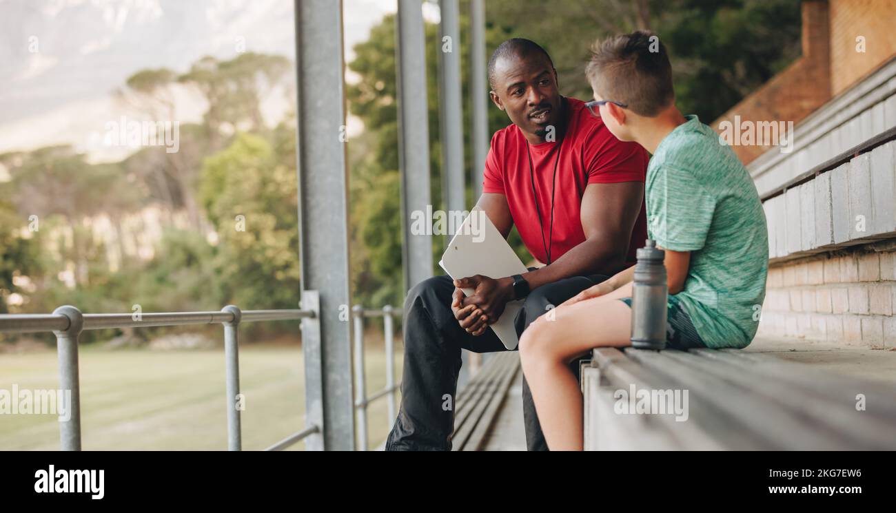 school coach talking a young student while sitting outside. Physical ...