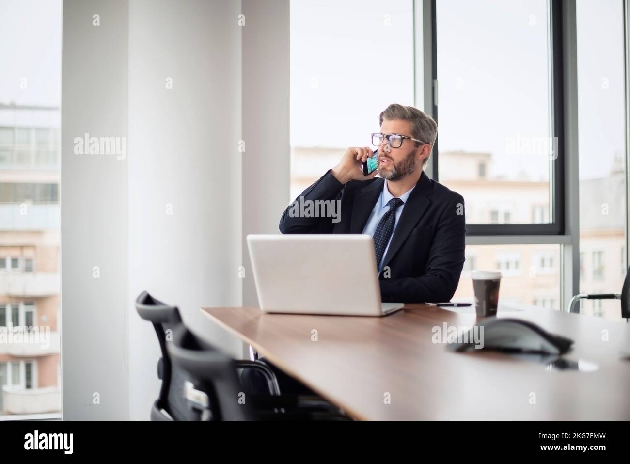 Mid adult business professional sitting at table with laptop and ...