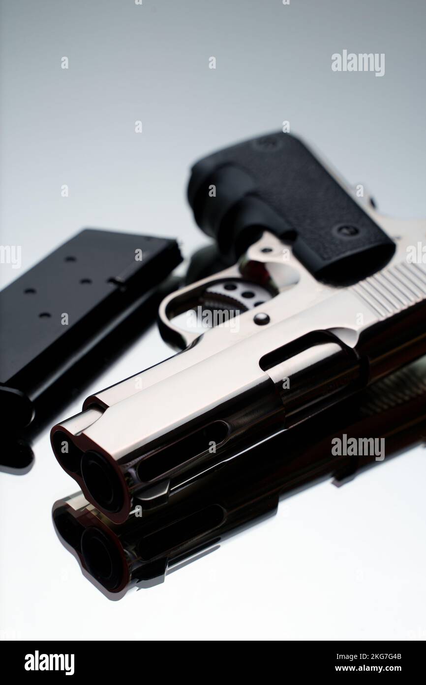 A vertical closeup of an isolated silver compact handgun on a white ...