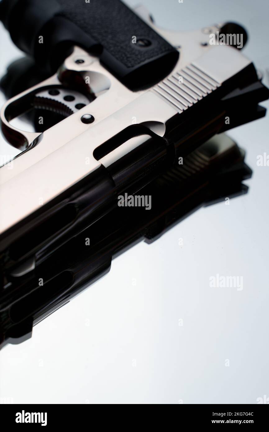 A vertical closeup of an isolated silver compact handgun on a white ...