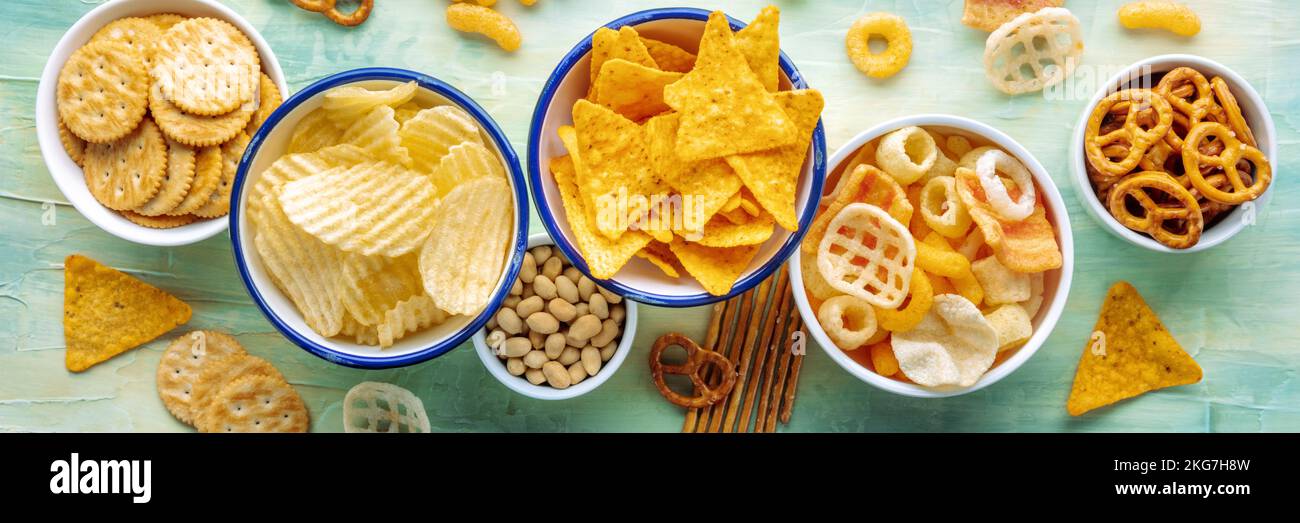 Salty snacks panorama. A table of assorted appetizers in bowls ...