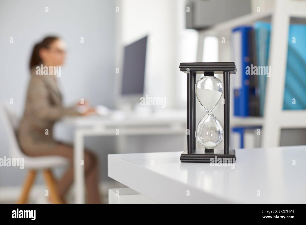 Sandglass at desk on office blur background with woman working on ...